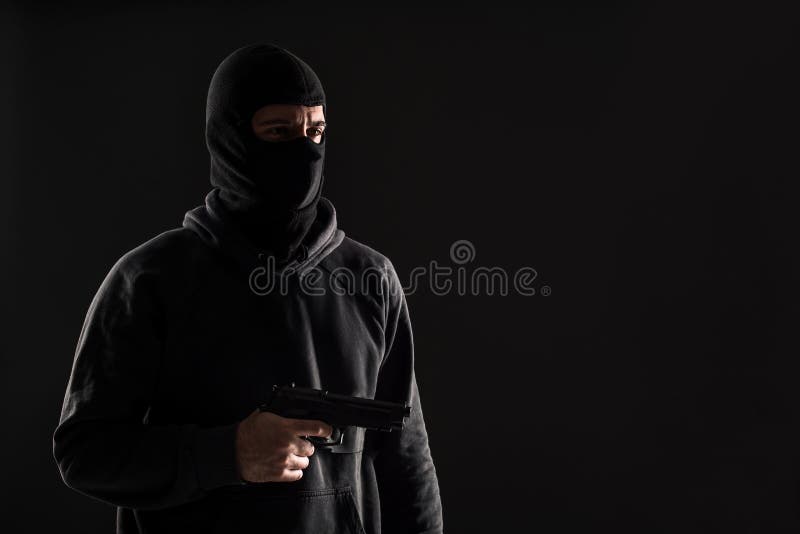 The Robber in a Mask with a Gun Pointed To the Side on a Black ...