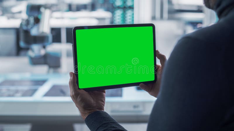 Robotics Engineer Using a Tablet Computer with Green Screen Mock Up Display Screen Running ...