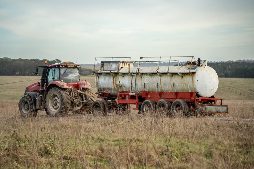 Robust Red Tractor Pulling a Pristine White Tanker Trailer Along a Flat ...