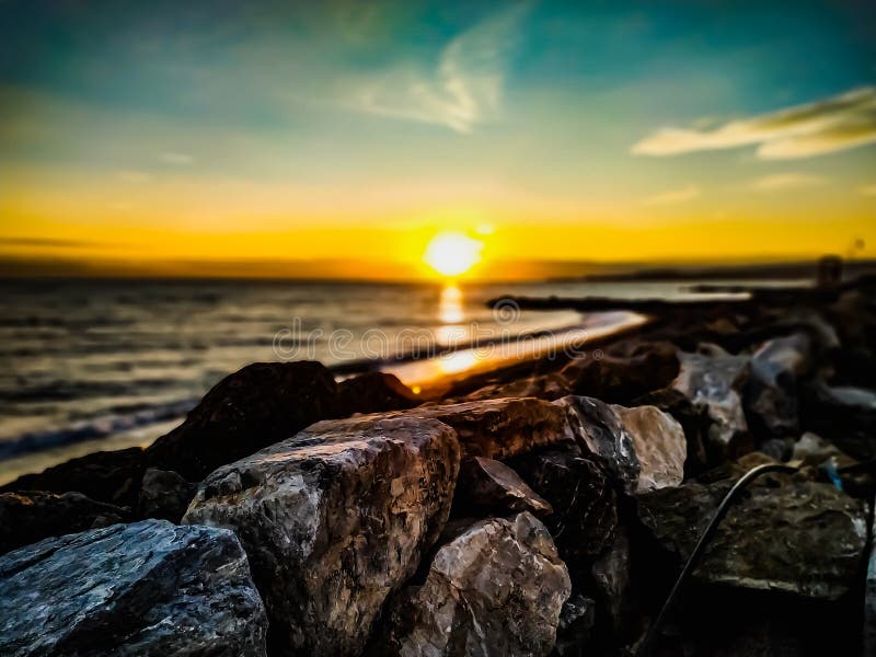 Rocks in a Beach with the Sun Behind Stock Image - Image of ocean ...