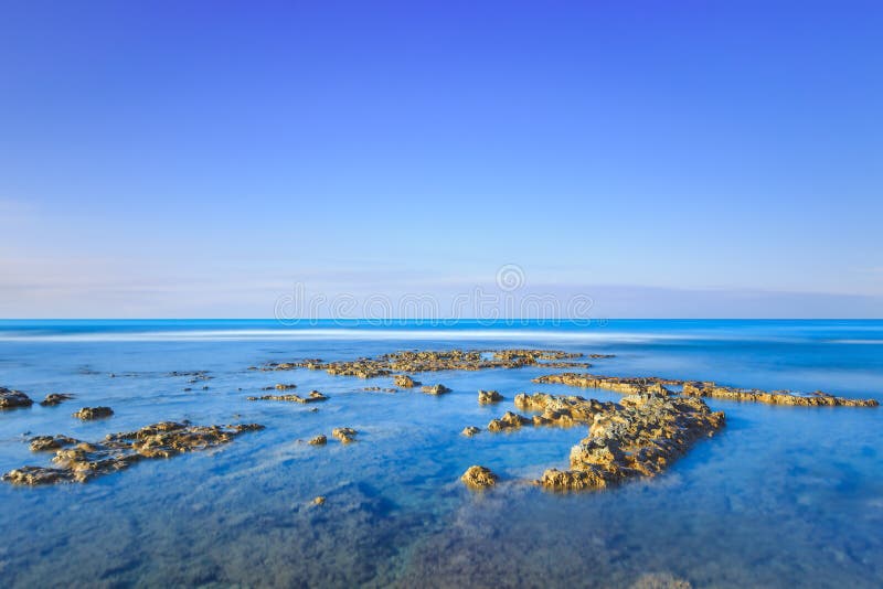 Rocks in a Blue Ocean Under Clear Sky on Sunrise. Stock Image - Image ...