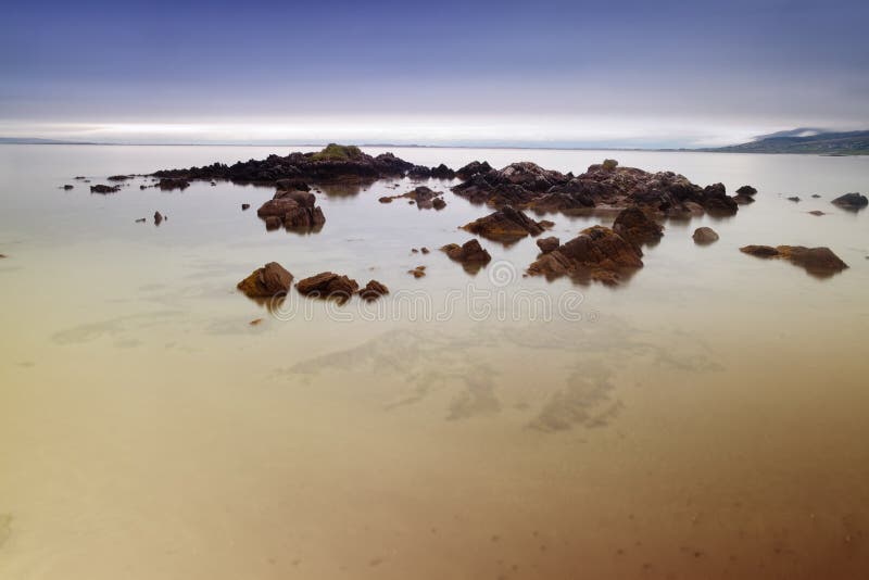 Rocks on Sandy Beach in Smooth Calm Sea Stock Photo - Image of ...