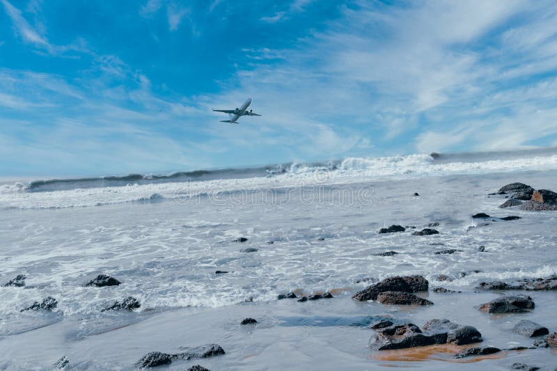 Rocks on the Seashore, Big Waves, Airplanes Flying in the Sky. Stock ...