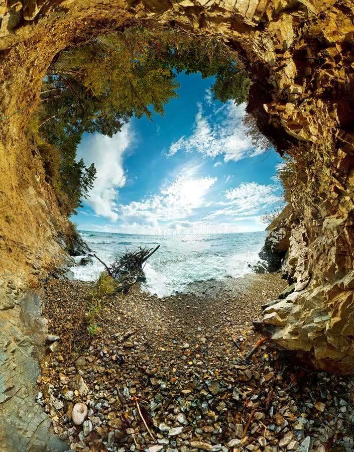 Rocky Cave with Trees Overlooking the Beach and Water from Lake Stock ...