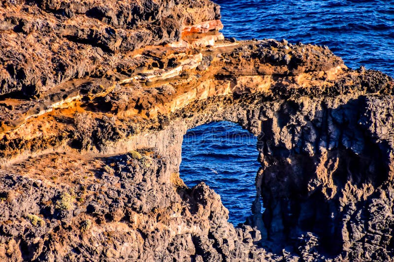 A Rocky Cliff with a Small Hole in it Overlooking the Ocean Stock Photo ...