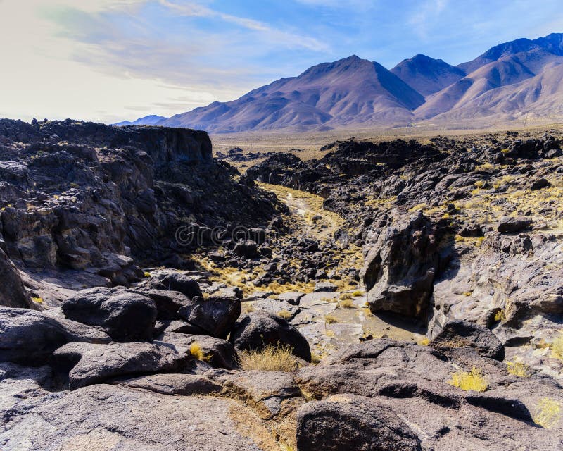 Rocky Cliffs with Dry Riverbed Below and Mountains Beyond Stock Photo ...