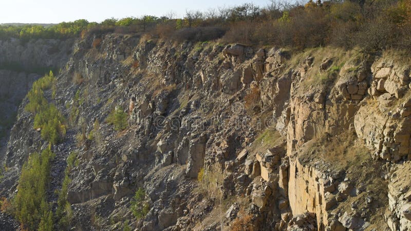A Rocky Cliffside with Sparse Vegetation, Including Dry Bushes and a ...