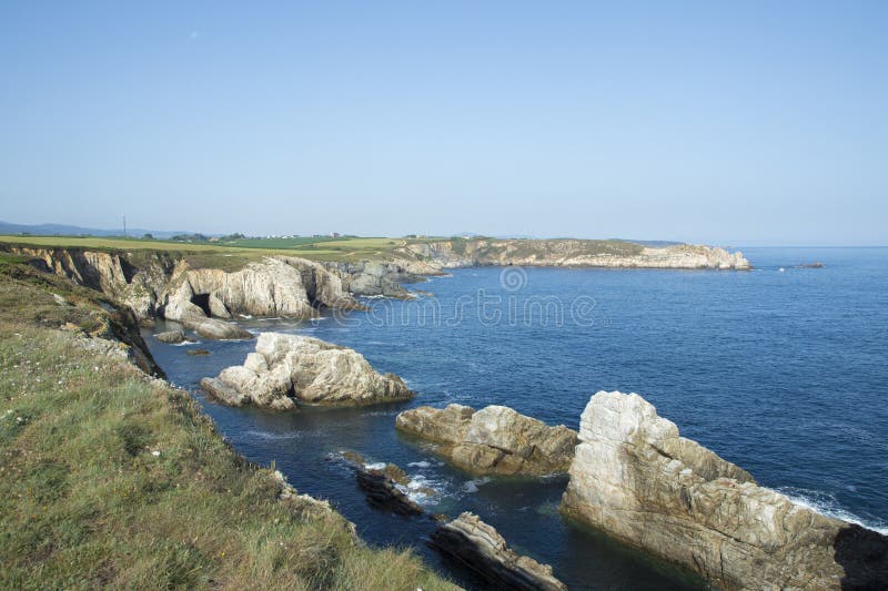 Rocky Coastline with Large Cliffs, Deep Blue Calm Water, and a Clear ...