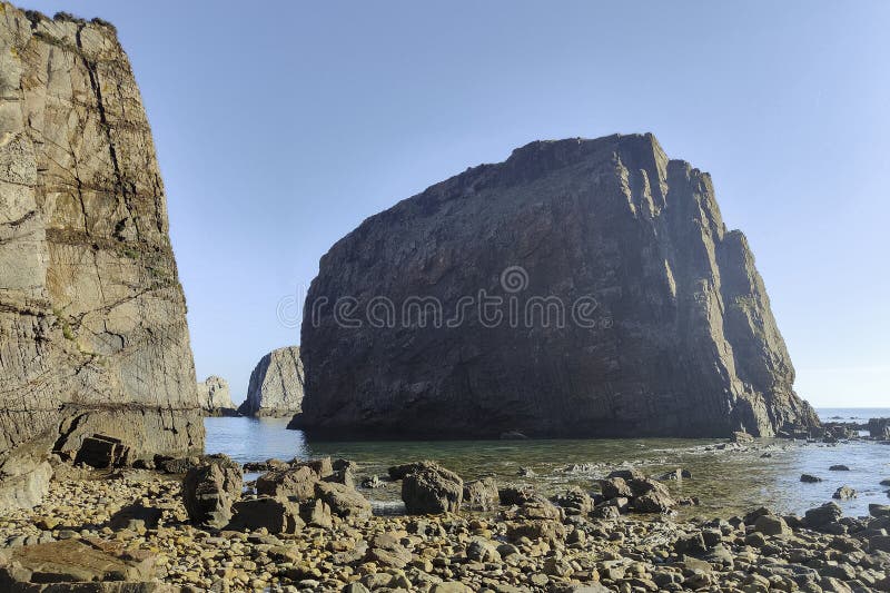 A Rocky Coastline with Large Cliffs Under a Clear Blue Sky and Calm ...