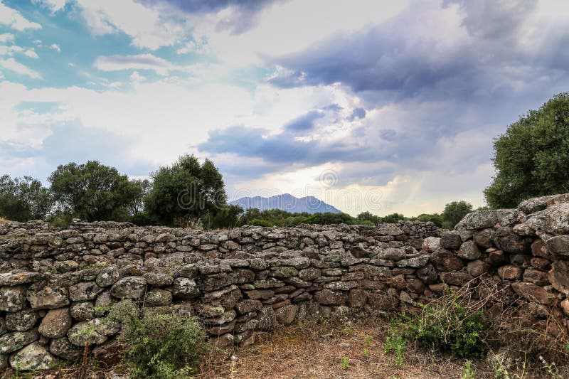 A Rocky Field with a Few Trees and a Cloudy Sky an Ancient Stone Gate ...