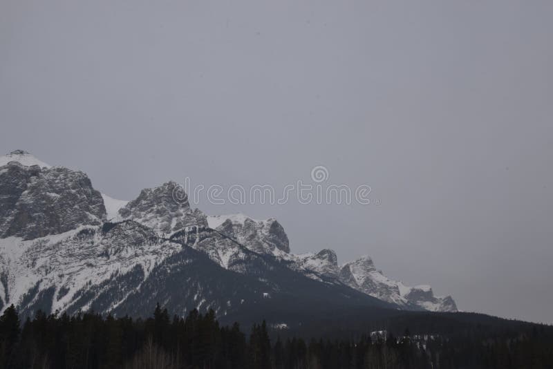 Snow Covered Rocky Mountains with Hazy Grey Sky Stock Photo - Image of ...