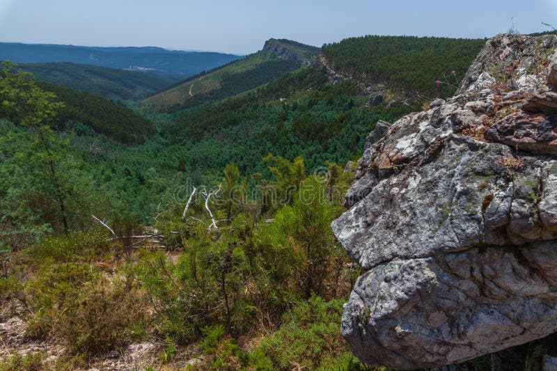 A Rocky Outcrop Overlooks a Dense Forested Valley with Rolling Hills ...