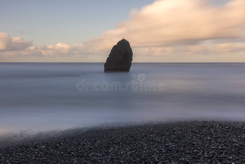 A Rocky Shoreline with a Large Rock in the Middle of the Water Stock ...
