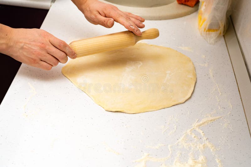 Roll Out the Dough. Baker Rolls Out the Dough on a Wooden Kitchen Table ...