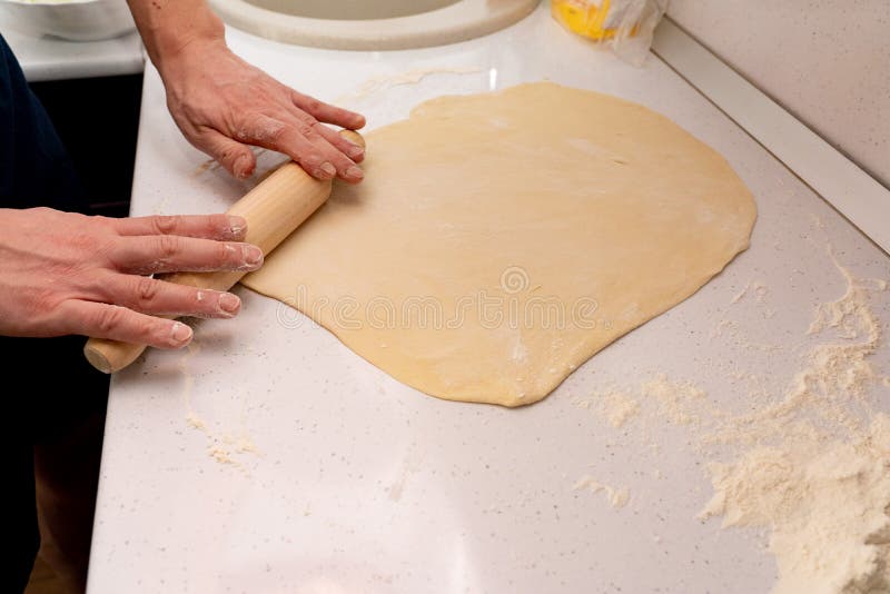 Baker Rolls Out the Dough on a Wooden Kitchen Table Sprinkled with ...