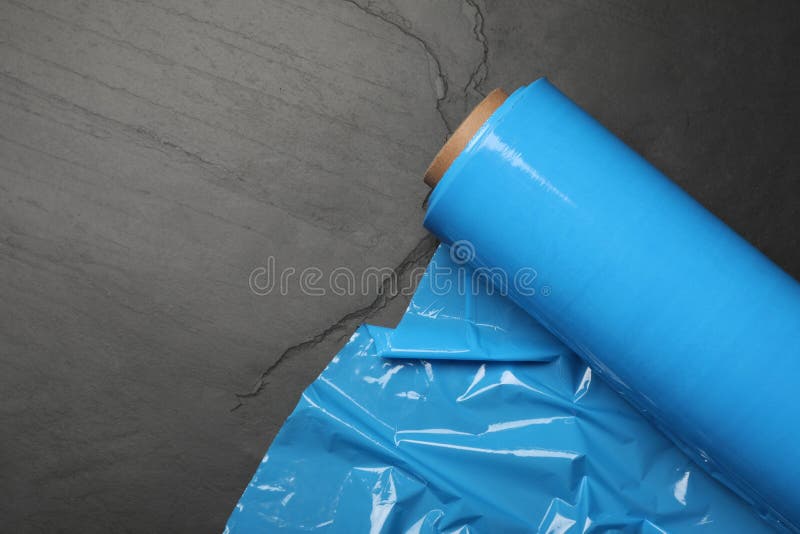 Roll of Plastic Stretch Wrap Film on Black Table, Top View. Space for ...