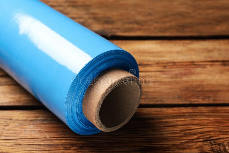 Roll of Plastic Stretch Wrap Film on Wooden Table, Closeup Stock Photo ...