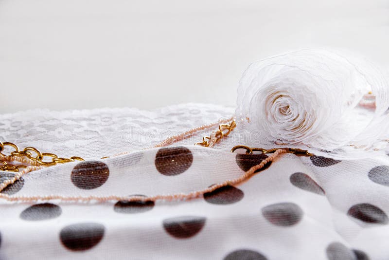 A Roll of White Lace and a Costume Chain on a Polka-dot Fabric in Close ...