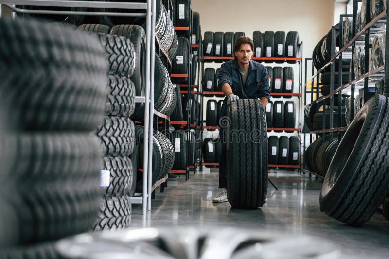 Rolling the Wheel. Man is in the Tire Fitting Car Service Stock ...