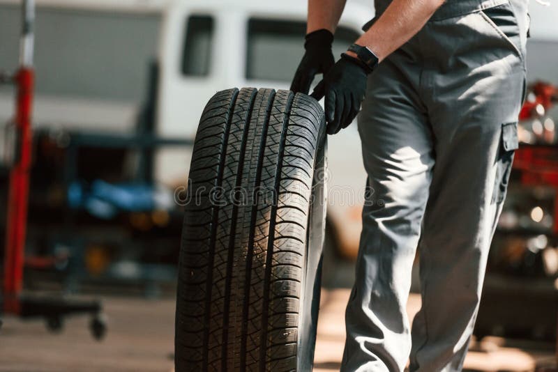 Rolling the Wheel. Man is Works in the Automobile Repairing Salon Stock ...
