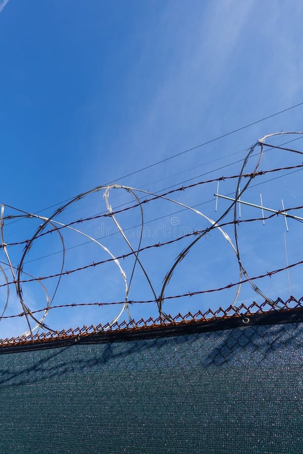 Rolls of Barbed Wire and Razor Wire on Top of a Chain Link Fence with a ...