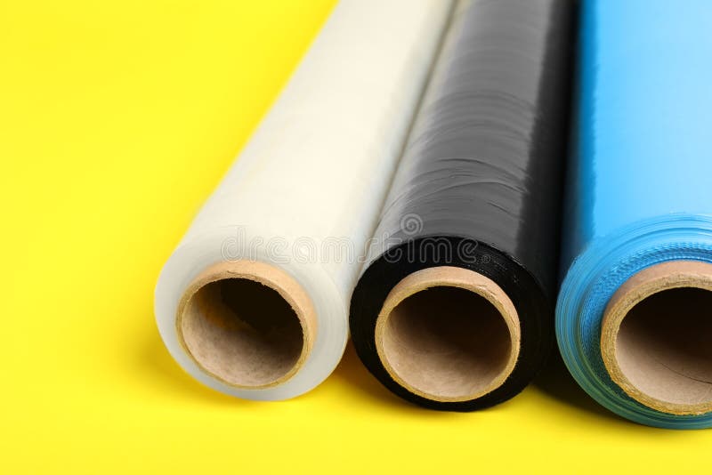 Rolls of Different Stretch Wrap on Yellow Background, Closeup Stock ...