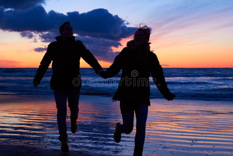 Romance at Sunset. Silhouette of a Couple Running on the Beach at ...