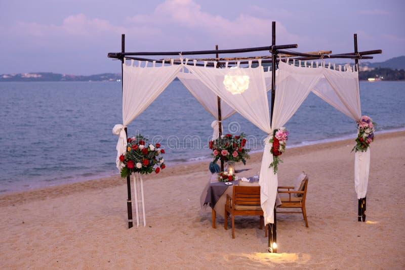 Romantic Beachside Dinner Setup Under a Canopy with Floral Decorations ...