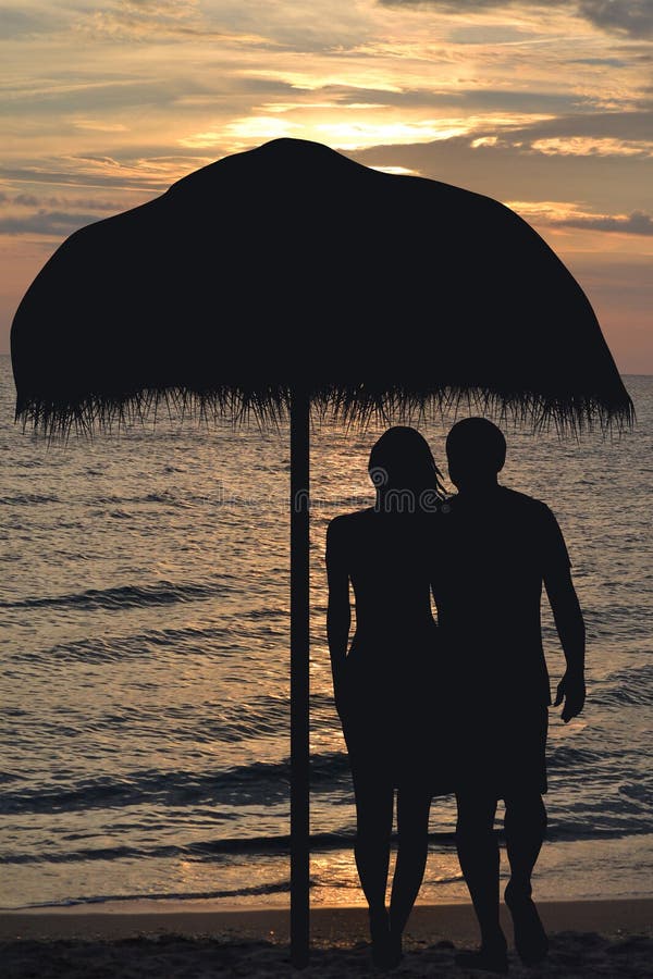Romantic Couple on the Beach Under Straw Umbrella Hugging at Sunrise ...