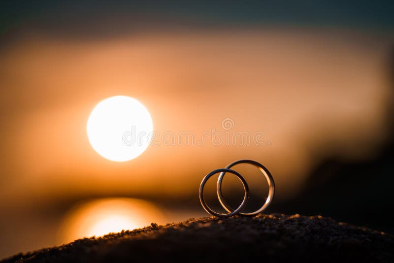 Romantic Wedding Two Gold Rings Balancing Upright Over a Sunset Stock ...