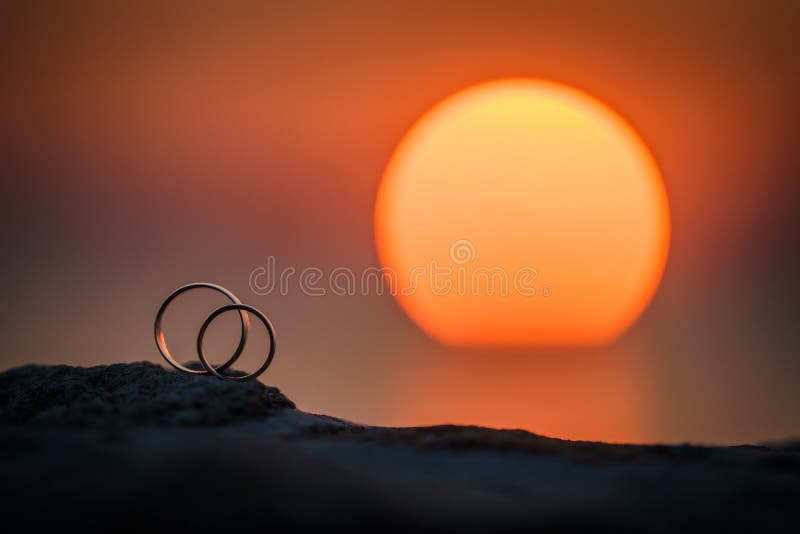 Romantic Wedding Two Gold Rings Balancing Upright Over a Sunset Stock ...