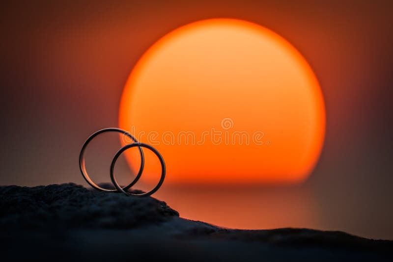 Romantic Wedding Two Gold Rings Balancing Upright Over a Sunset Stock ...