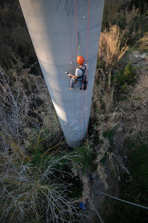 Rope Access Technician Inspecting Concrete Bridge Pillar Using Power ...