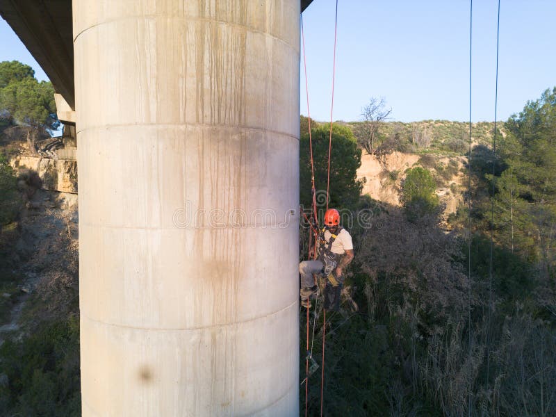 Rope Access Technician Inspecting Concrete Bridge Pillar Using Ropes ...