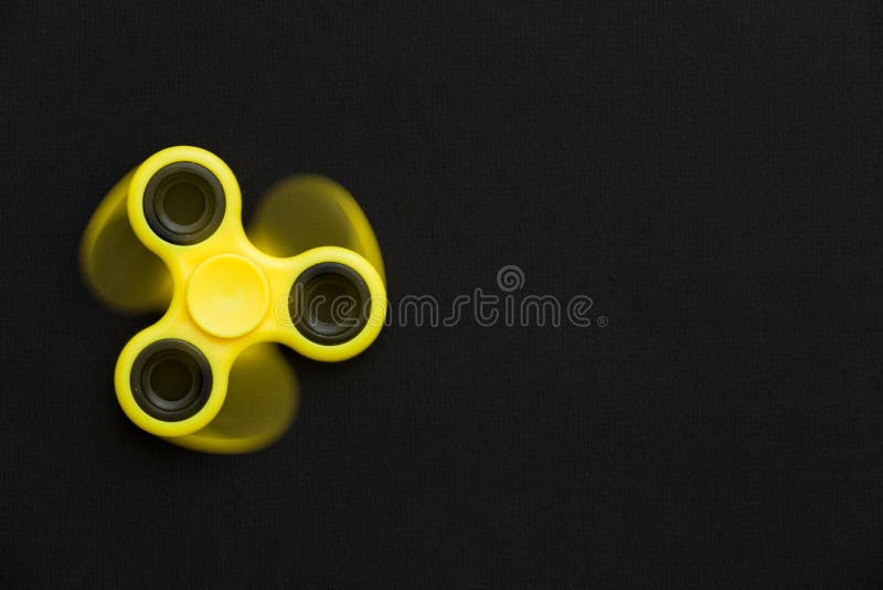 Rotating Yellow Fidget Spinner Device on Black Background. Top View ...