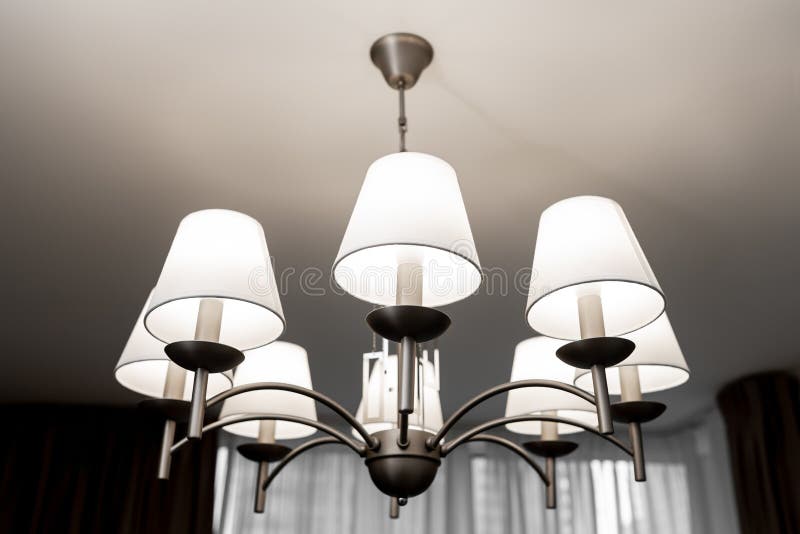 A Round Chandelier of Several Lamps Against a Light Ceiling, Full Frame ...