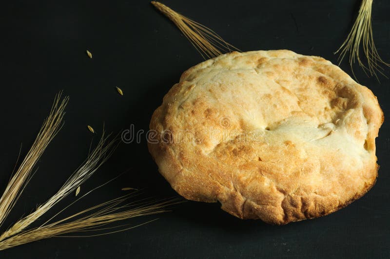 Round Flat Bread on a Black Background with Ears of Rye. Natural Light ...