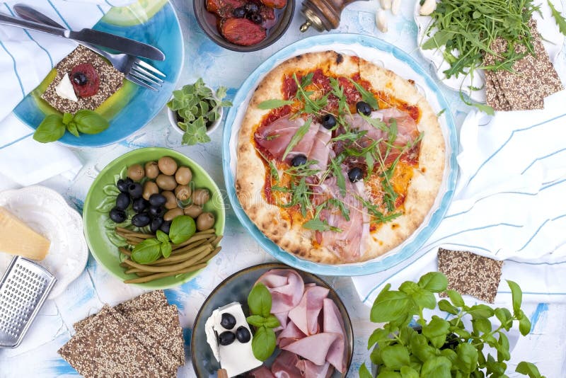 Round Large Pizza from the Oven with Prosciutto and Olives, Arugula and ...