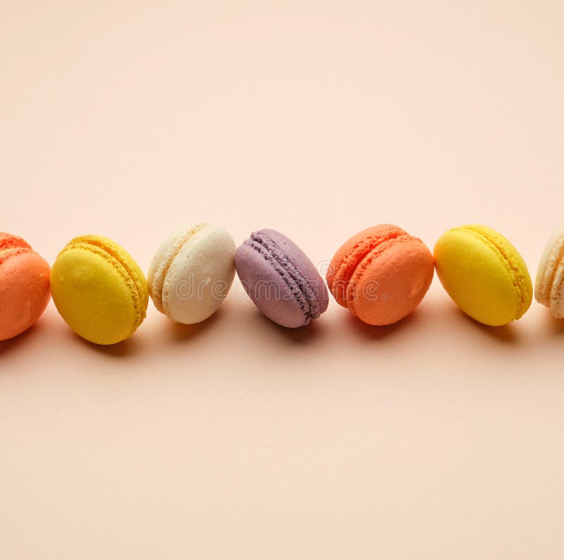 Round Multi-colored Baked Macarons With Cream Lie In A Line On A Beige ...