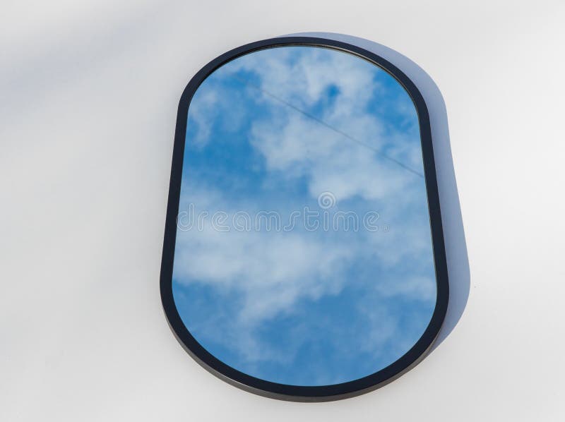 A Round or Oval Mirror with a Reflection of the Blue Sky and White ...