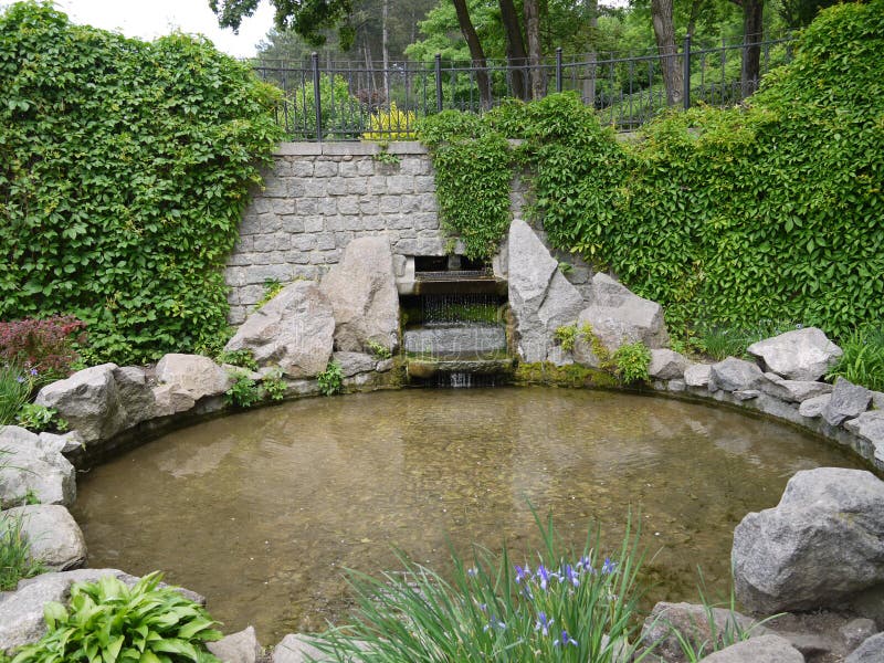 A Round, Small Pond Surrounded by Stones, with a Small Waterfall Stock ...