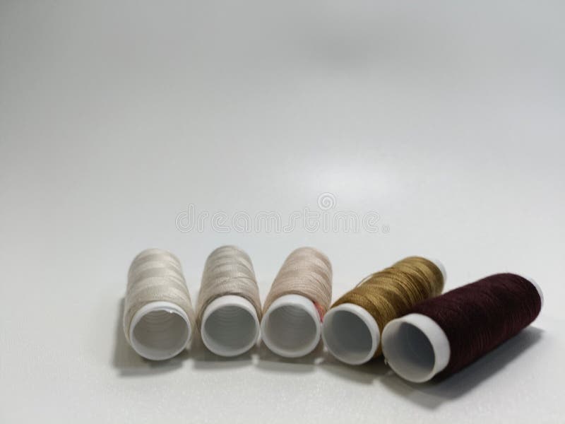 Row of Beige, Gold, and Burgundy Sewing Thread Spools on White ...