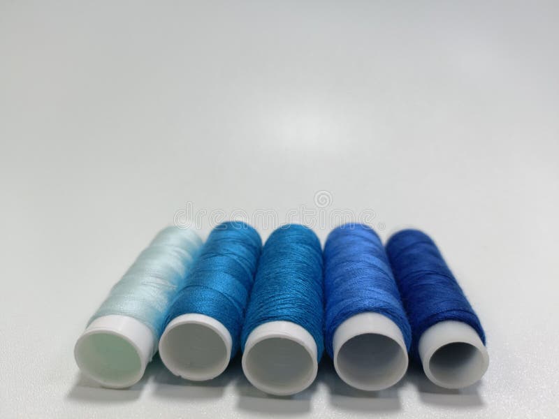 Row of Blue Sewing Thread Spools in Gradient Shades on White Background ...