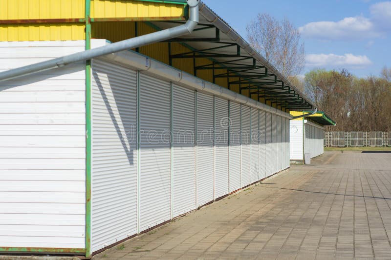 A Row of Closed Market Stalls with White Shutters with Blue Sky Stock ...