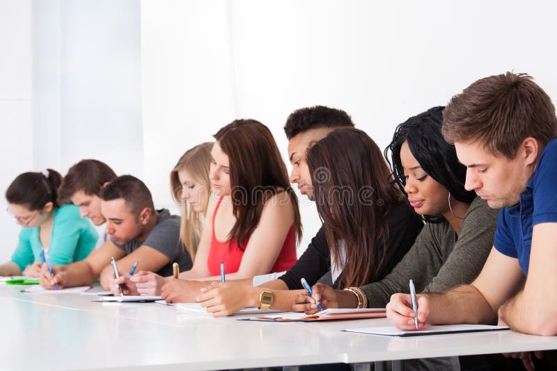 Row of College Students Writing at Desk Stock Image - Image of person ...