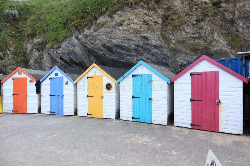 Row of Colorful Beach Huts Next To a Rocky Cliff Covered with Greenery ...