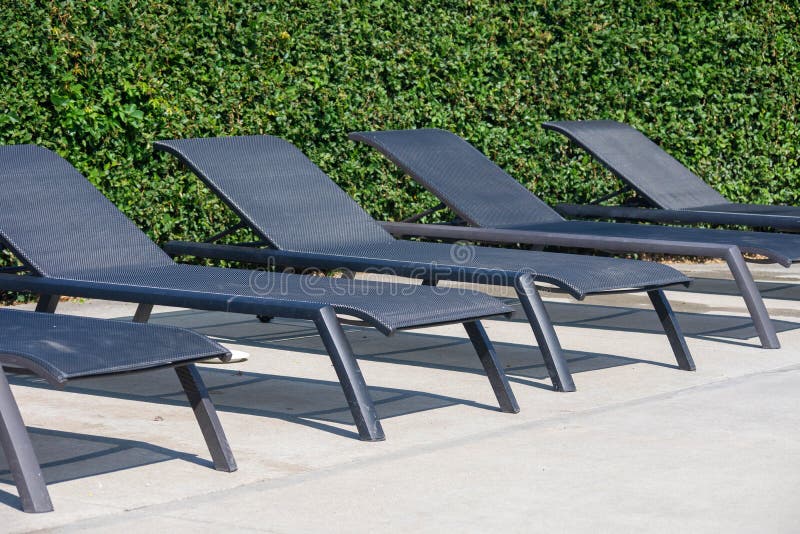 A Row of Empty Pool Chairs for Lying Down with a Green Background on a ...