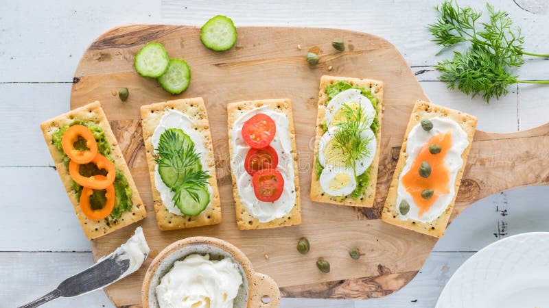 A Row of Everything Crackers with Various Fresh Toppings, on a Wooden ...