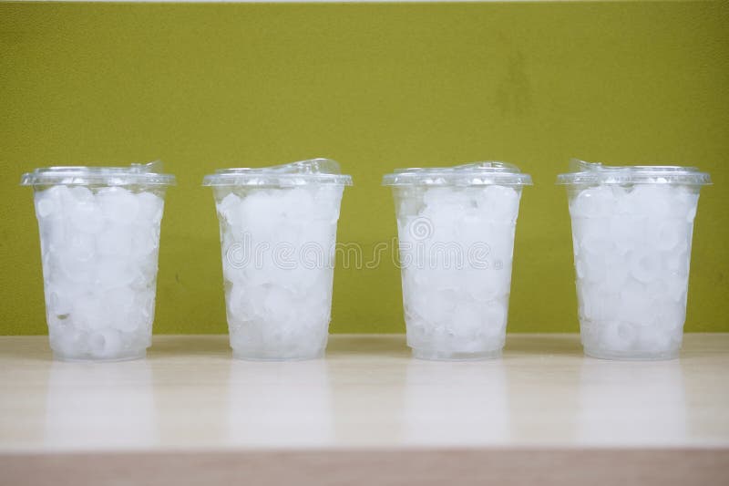 A Row of Four Clear Plastic Cup with Lid Filled with Ice Cubes Stock ...