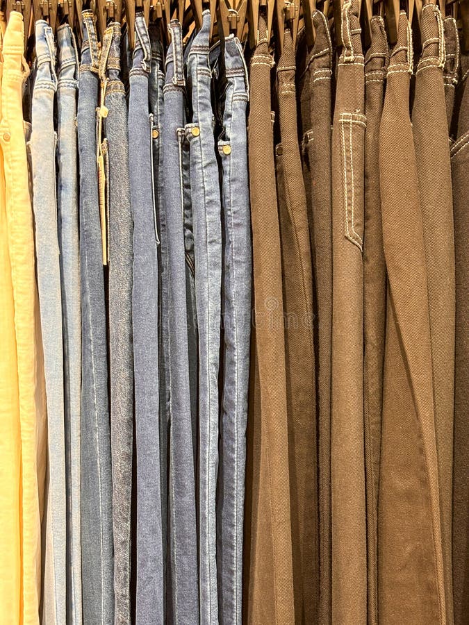 A Row of Jeans Hanging on a Rack, with Some in Blue and Some in Brown ...